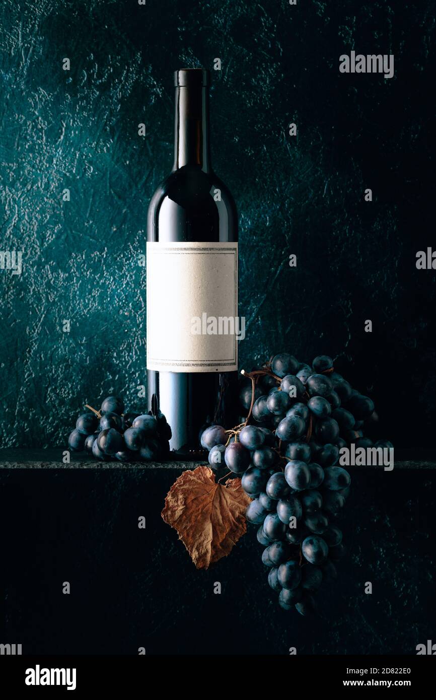 Flasche Rotwein mit dem alten leeren Etikett. Rotwein und blaue Trauben ...