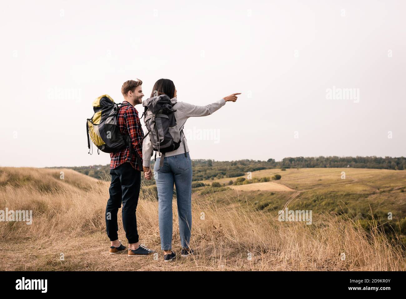 Lächelnder Wanderer, der die Hand der afroamerikanischen Freundin hält ...