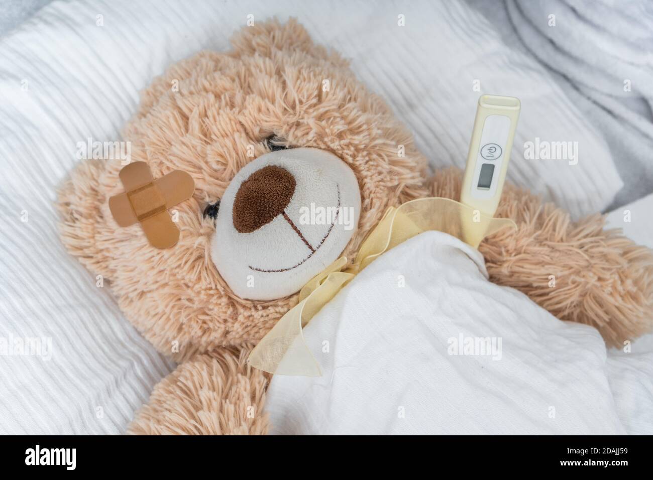 Kranker Teddybär mit Gips und Thermometer liegt im Bett Stockfotografie ...