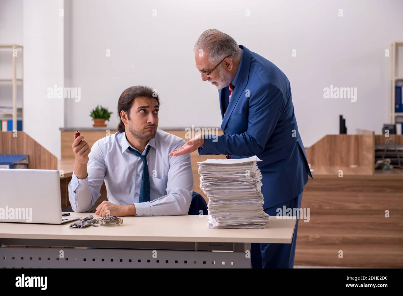 Junger männlicher Angestellter und alter Chef, der am Arbeitsplatz ...
