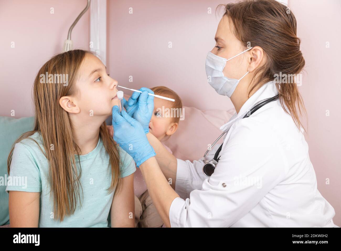 Pediatrician taking nasal mucus test sample from elementary age girl's ...