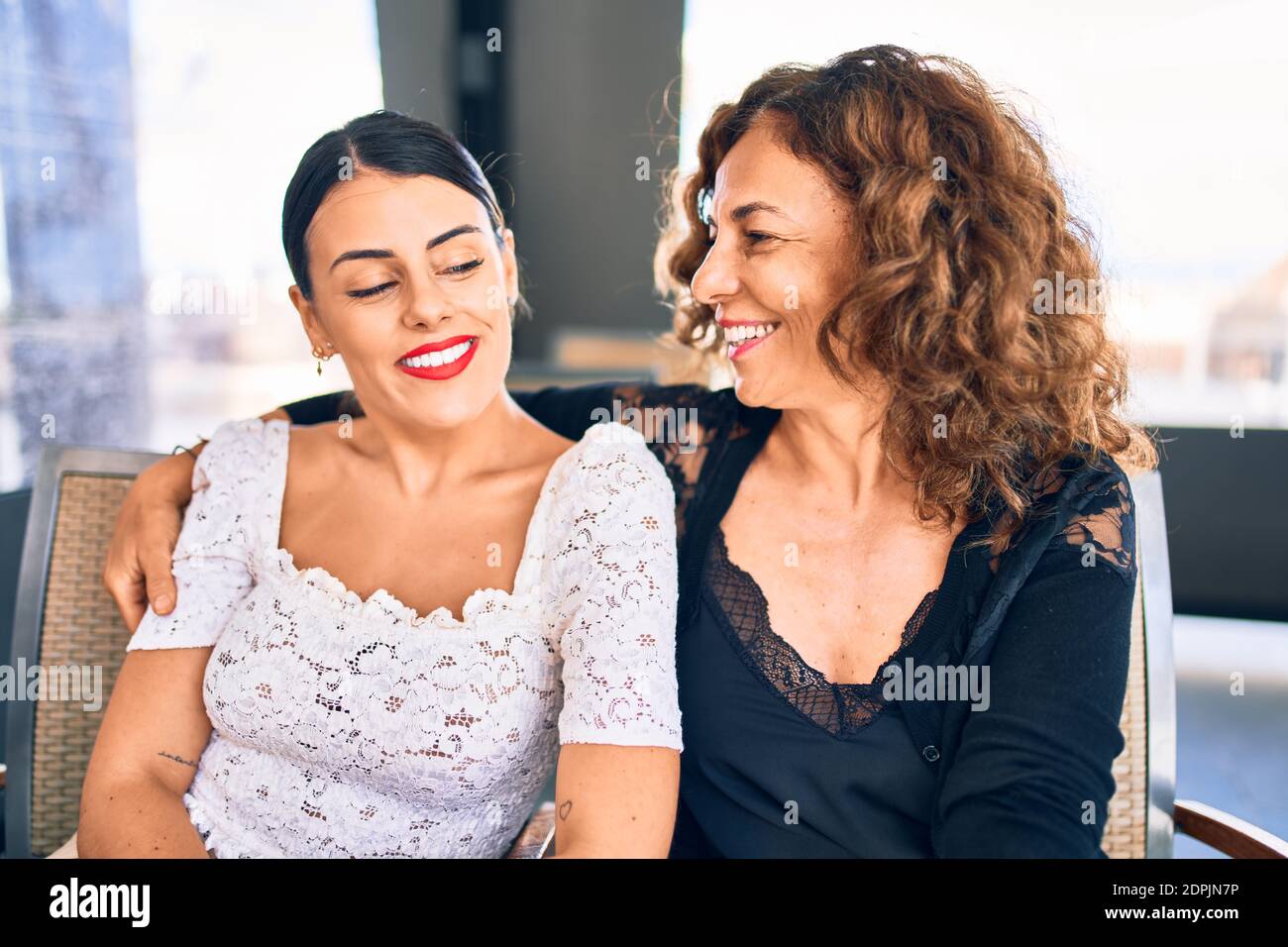 Schöne Mutter und Tochter lächeln glücklich und zuversichtlich. Sitzen ...