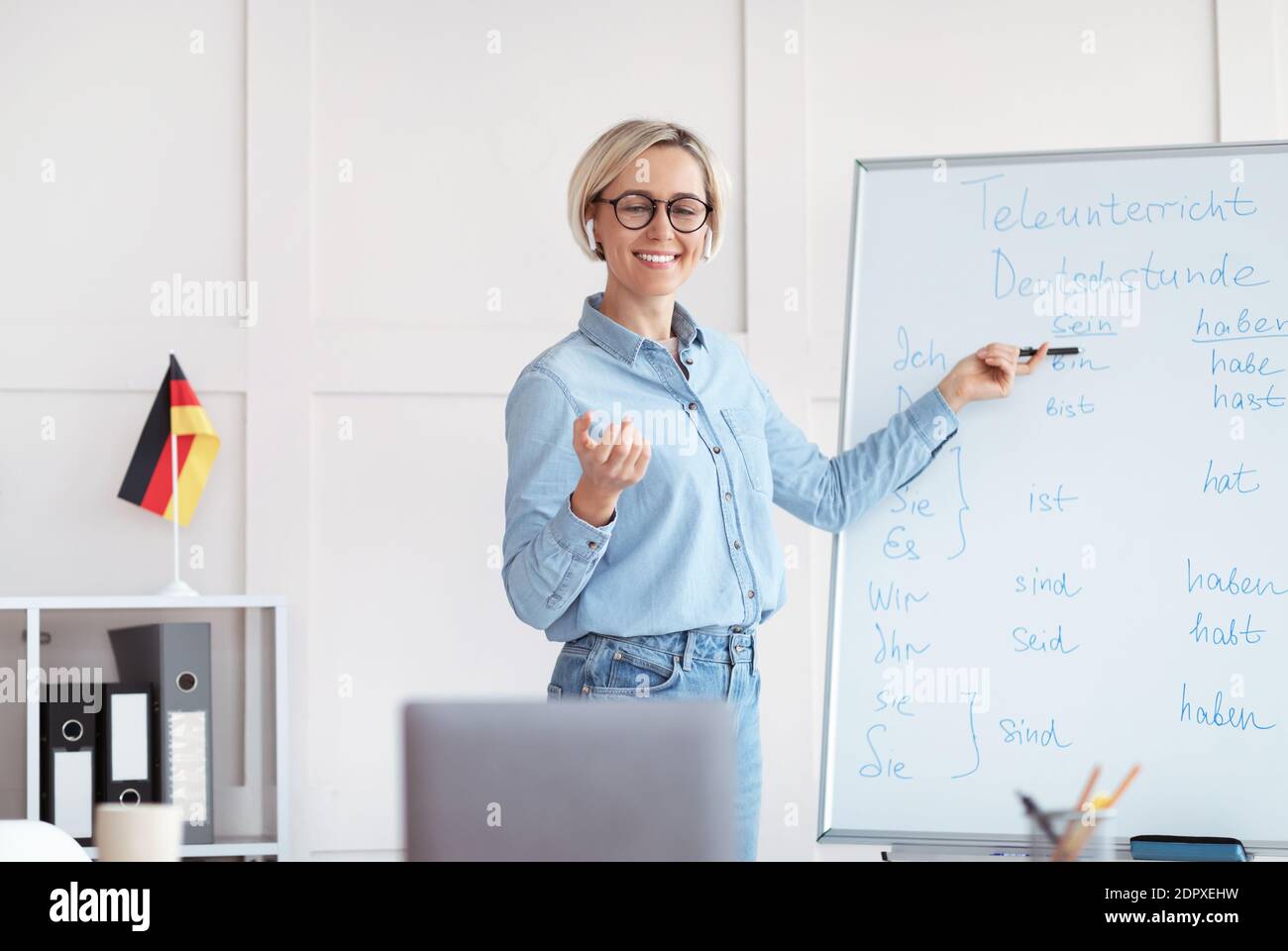 Freundliche junge Lehrerin, die online Deutschunterricht auf Laptop ...