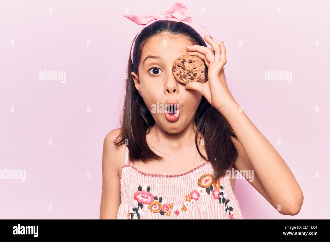 Schönes Kind Mädchen halten Cookie verängstigt und erstaunt mit offenem ...