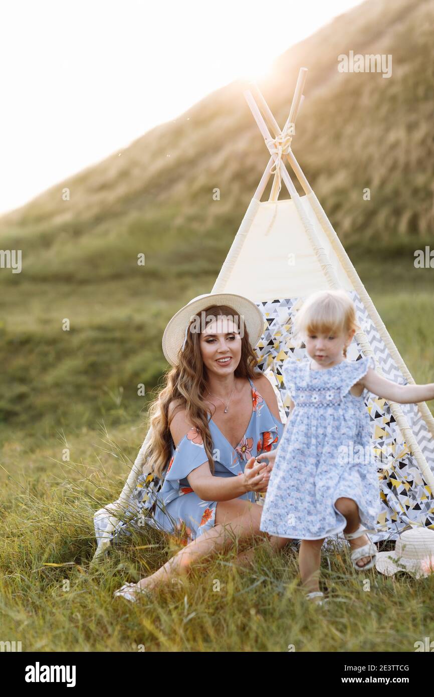 Schöne Mutter mit ihrer kleinen Tochter, die in der Nähe von Wigwam auf ...