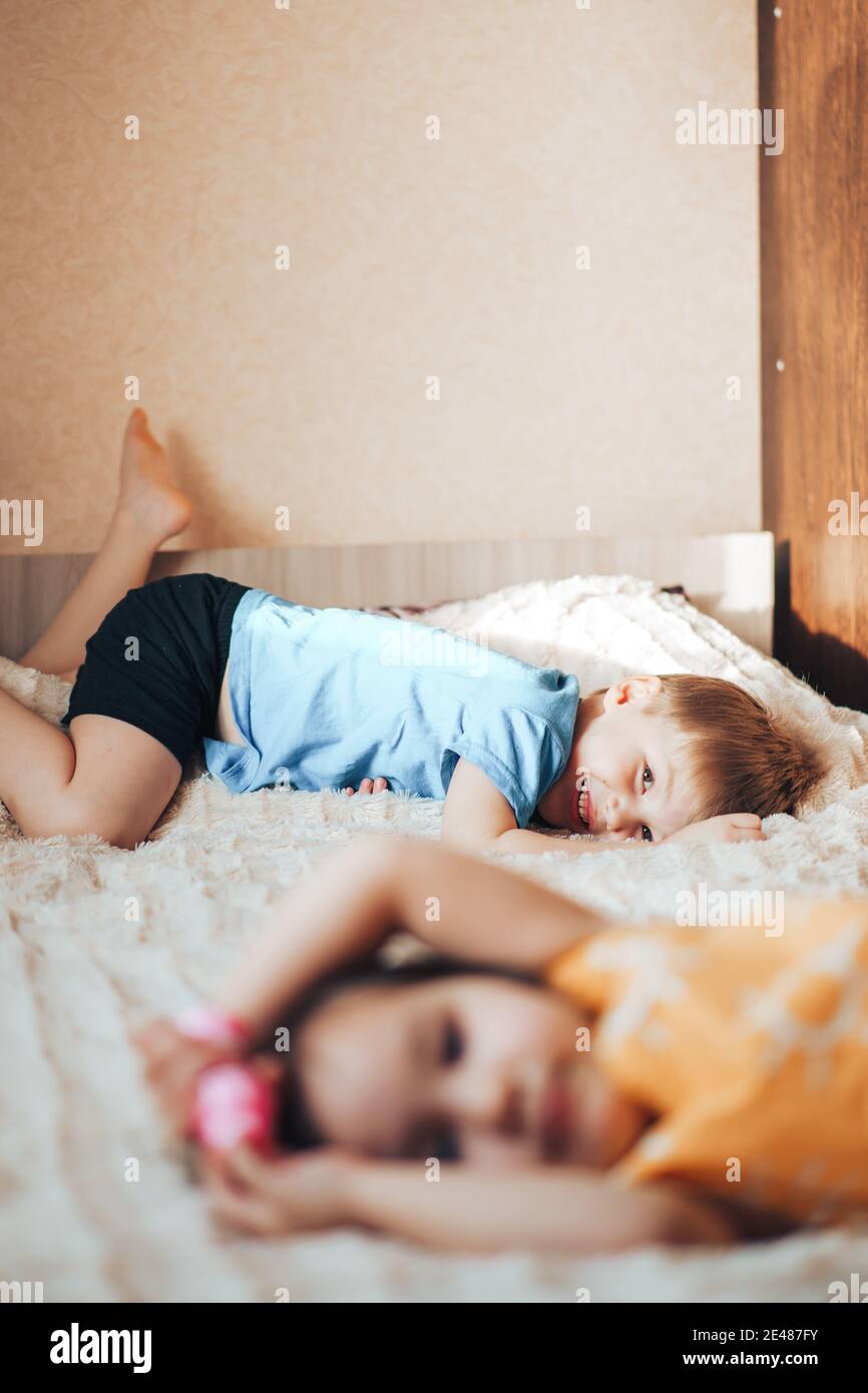 Kinder liegen auf dem Bett. Bruder und Schwester spielen auf dem Bett. Erziehung und Betreuung ...