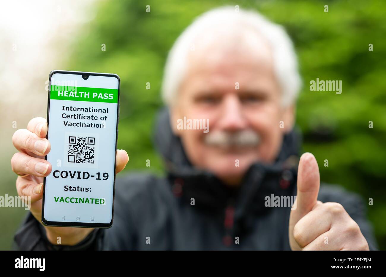 Älterer Mann zeigt einen Gesundheitsausweis auf einem Handy, was auf ... Älterer Mann zeigt einen Gesundheitsausweis auf einem Handy, was auf ...