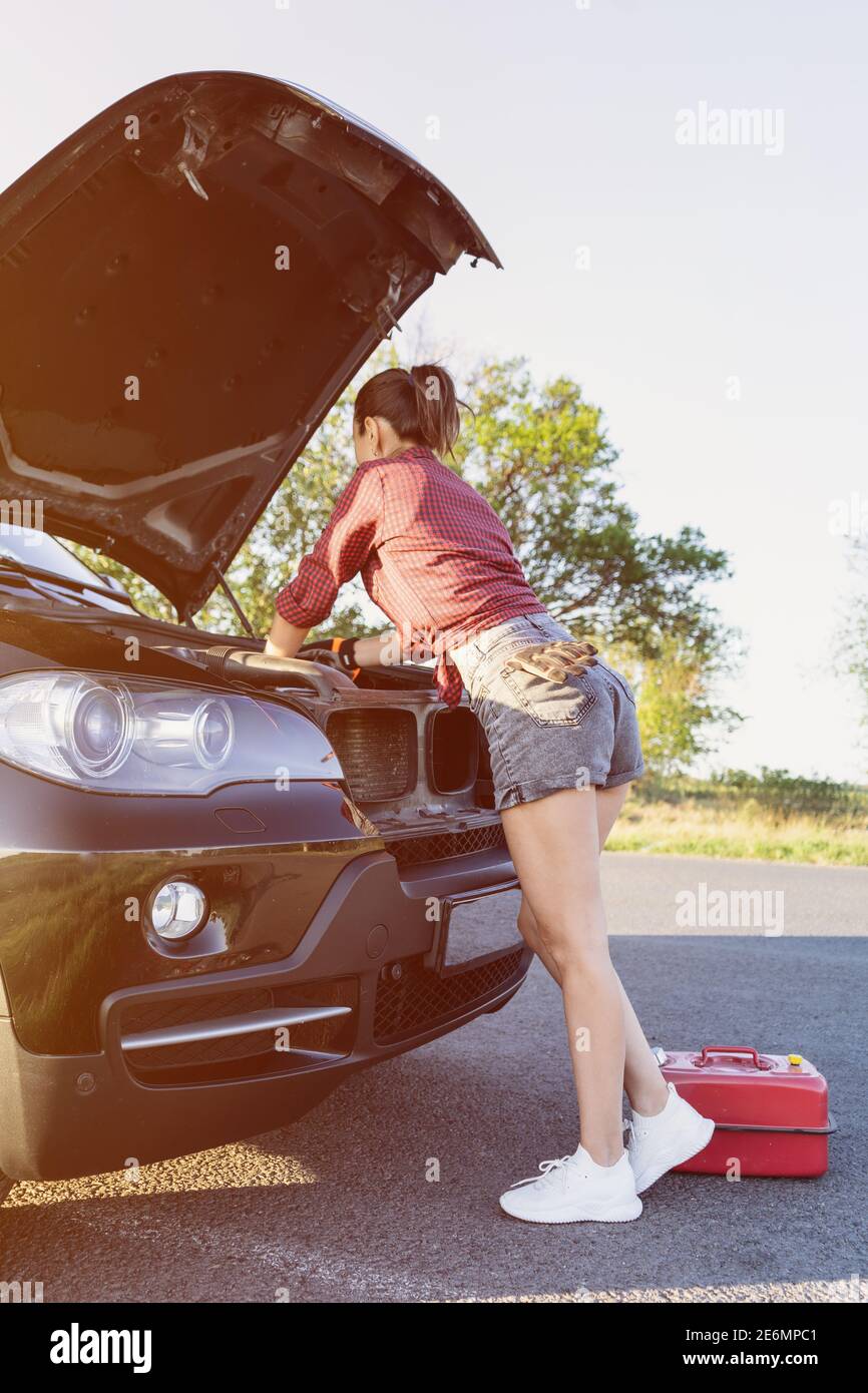 Schöne junge Frau Befestigung des Autos am Straßenrand. Mädchen in Hemd ...