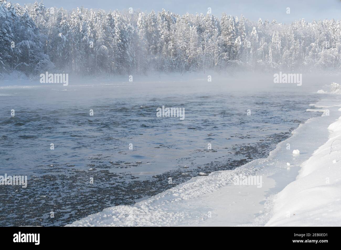 Frostiger Nebel über dem Winterfluss mit Schnee und Wald am Ufer ...