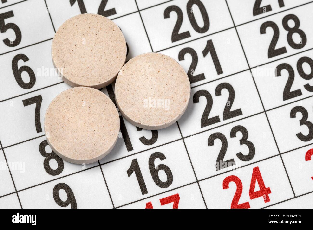 Drei medizinische Tabletten auf einem monatlichen Kalender ...