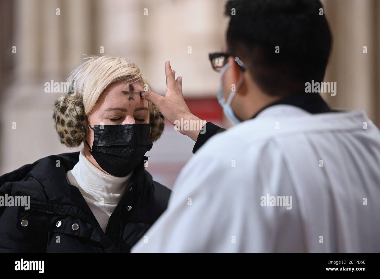 Ein Seminarist legt Asche auf die Stirn eines Kirchenbesuchers in der ...
