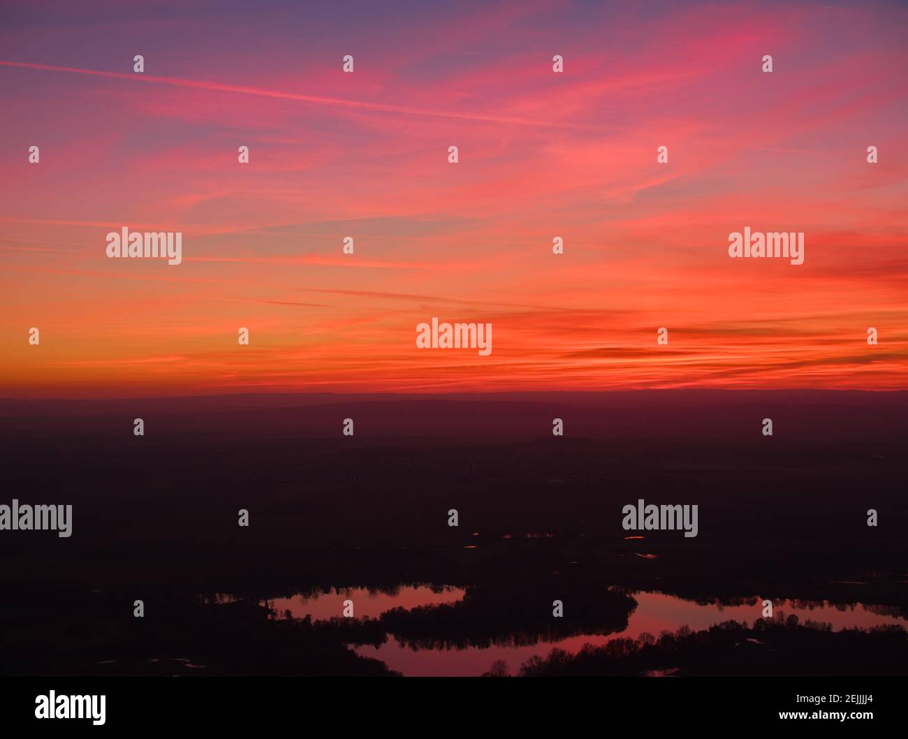 Rot-orange Himmel nach Sonnenuntergang. Rote Wolken spiegeln sich in ...