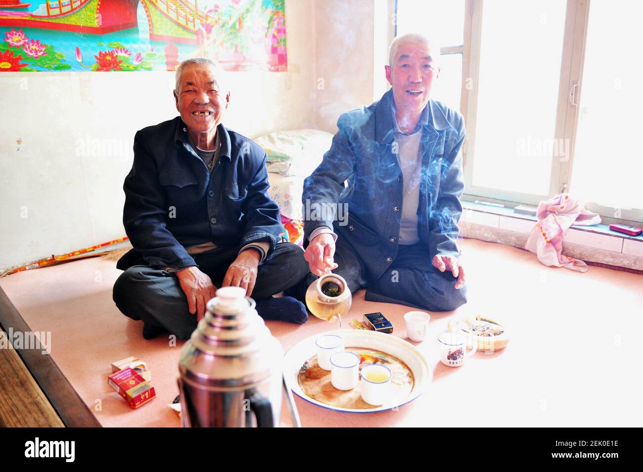 QINGDAO, CHINA - 20. APRIL 2020 - zwei ältere männliche Dorfbewohner trinken Tee und unterhalten ...