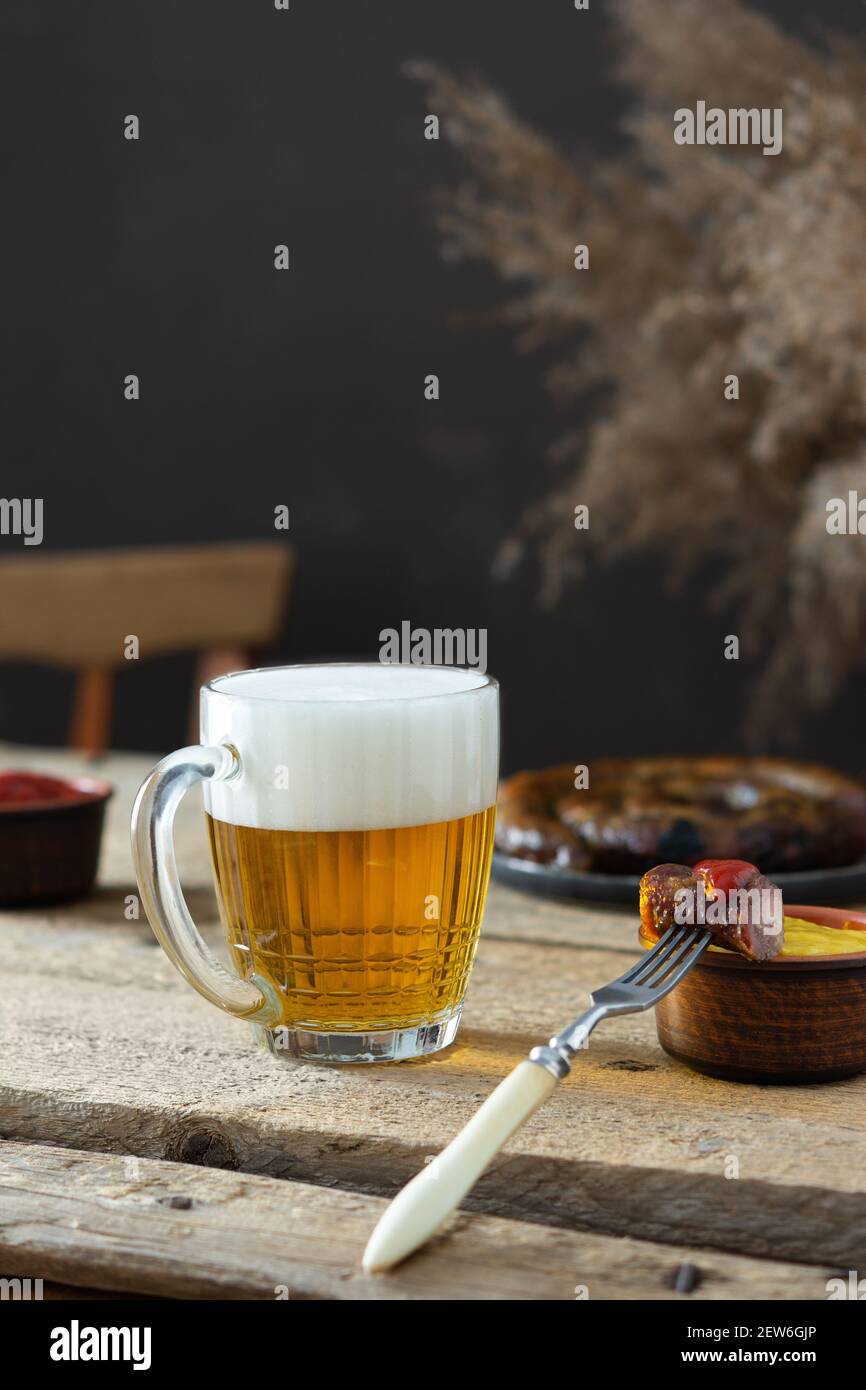 Glas mit Bier und Schaum und Gabel mit einem Stück Von Wurst und ...