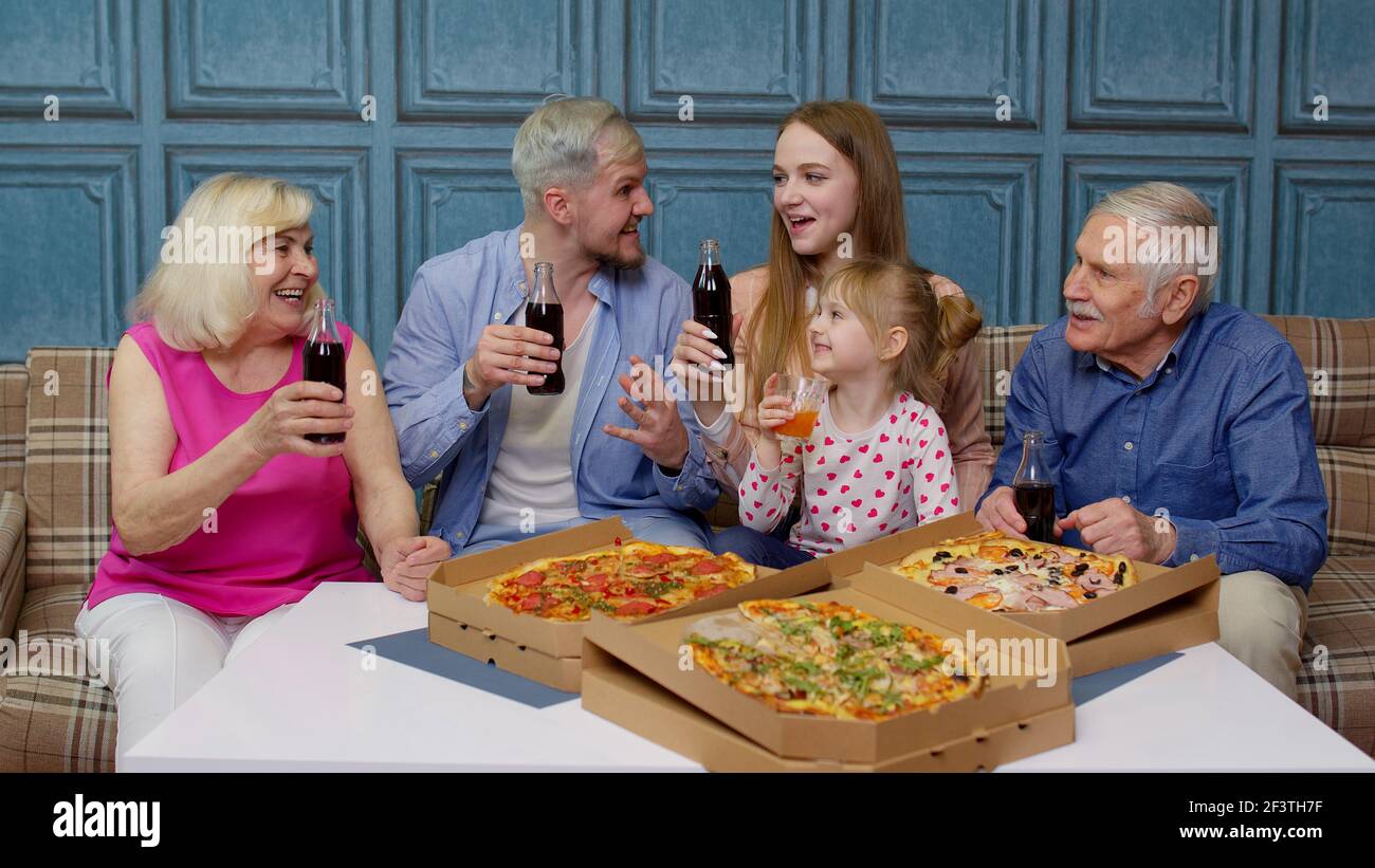 Glückliche Familie mit mehreren Generationen, die zu Hause eine Mittagsparty macht, Pizza isst ...