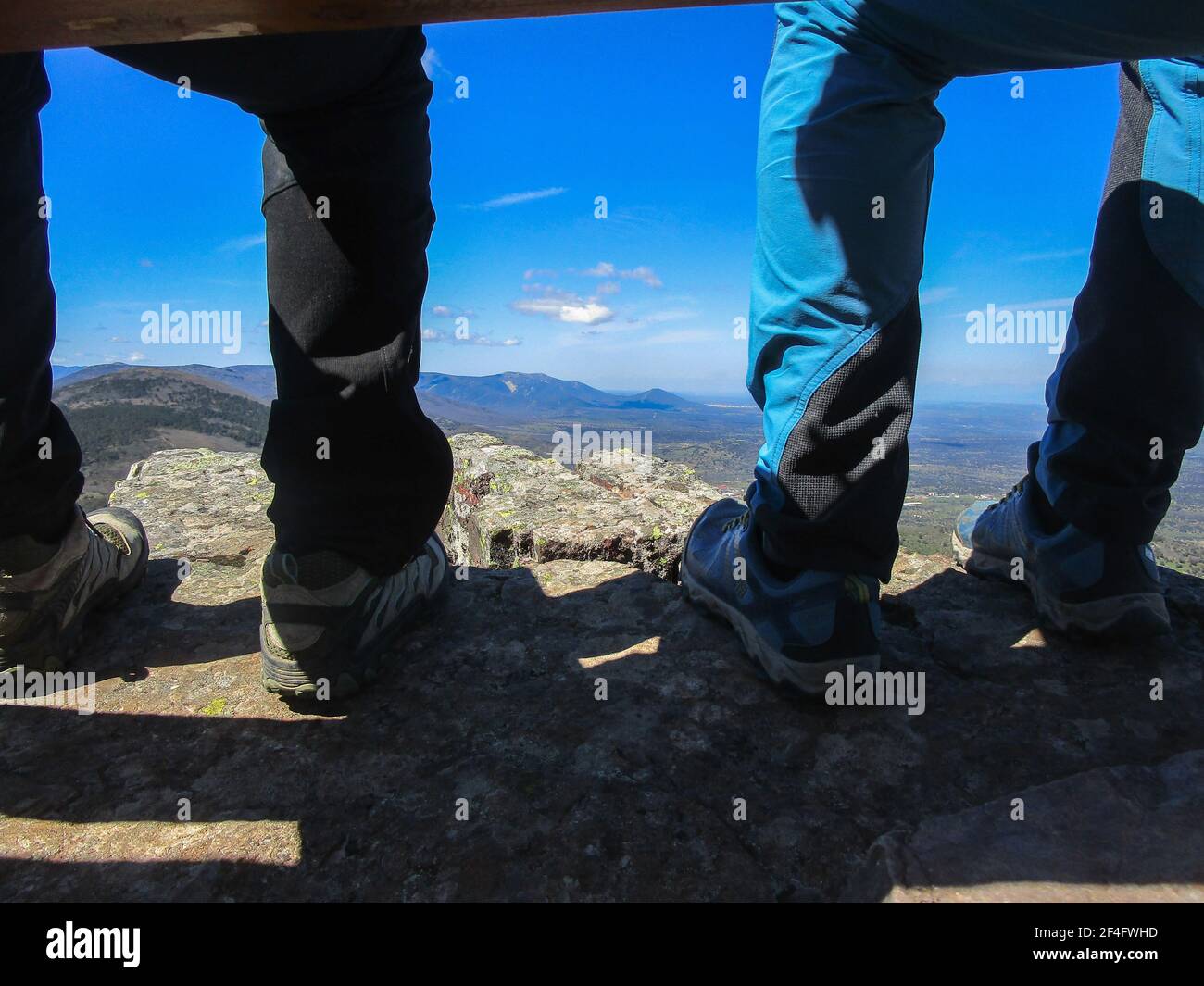 Eine Nahaufnahme der Beine von Bergsteigern, die auf einer Holzbank auf ...