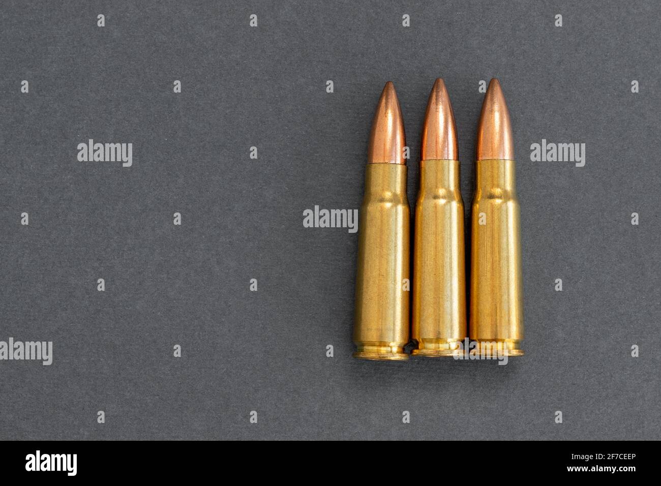 Drei Kugeln auf grauem Papierhintergrund. Patronen Kaliber 7.62 für ...