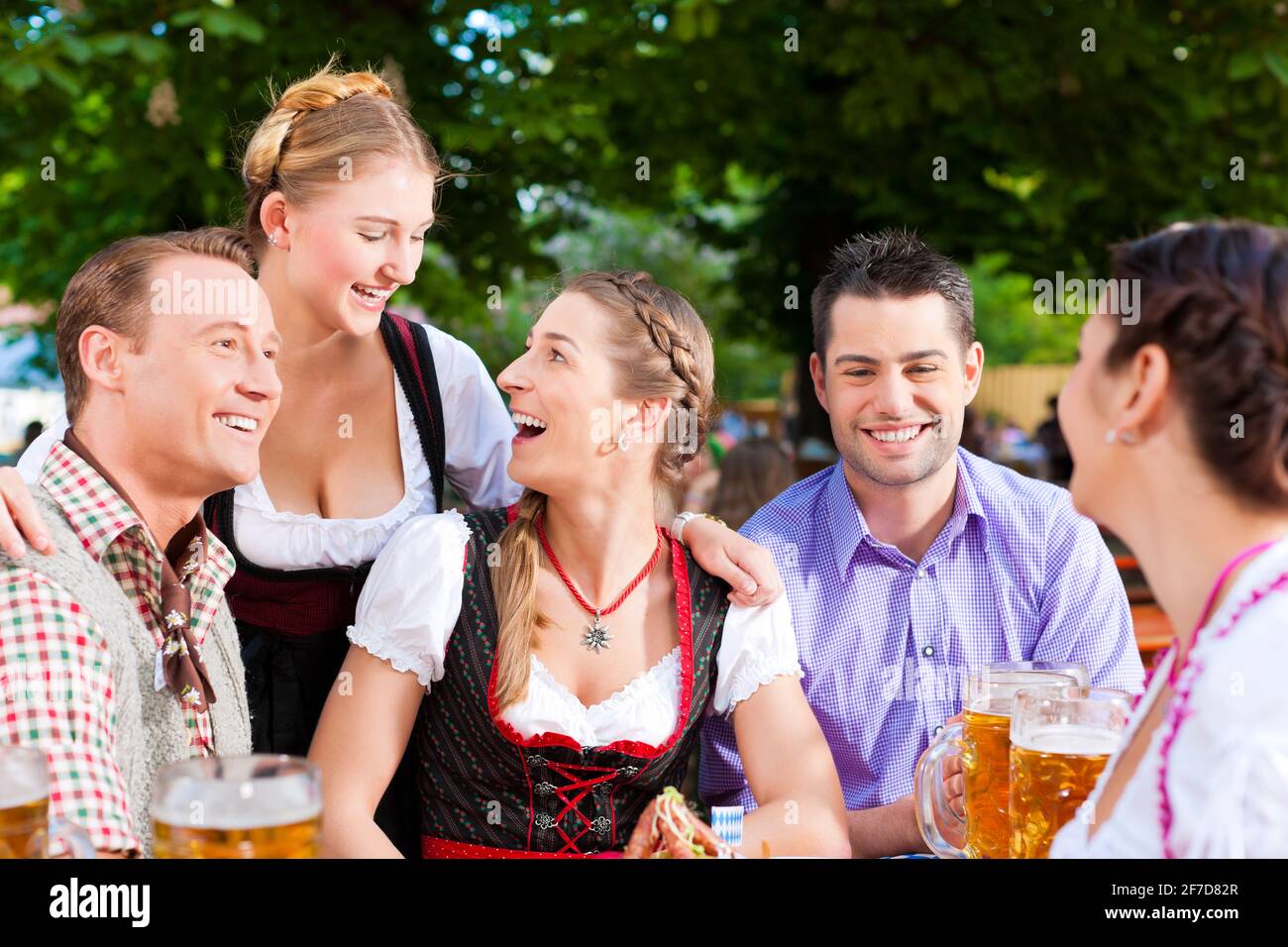 Im Biergarten - Freunde Tracht, Dirndl und auf einem Tisch mit Bier und ...