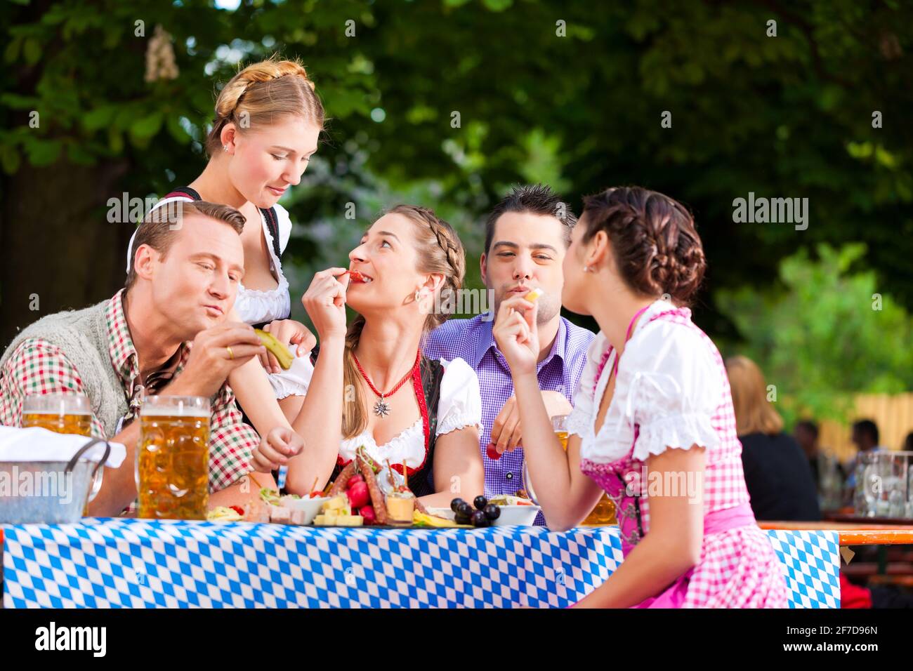 Im Biergarten - Freunde Tracht, Dirndl und auf einem Tisch mit Bier und ...