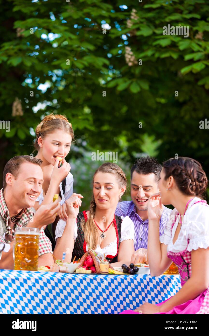Im Biergarten - Freunde Tracht, Dirndl und auf einem Tisch mit Bier und ...