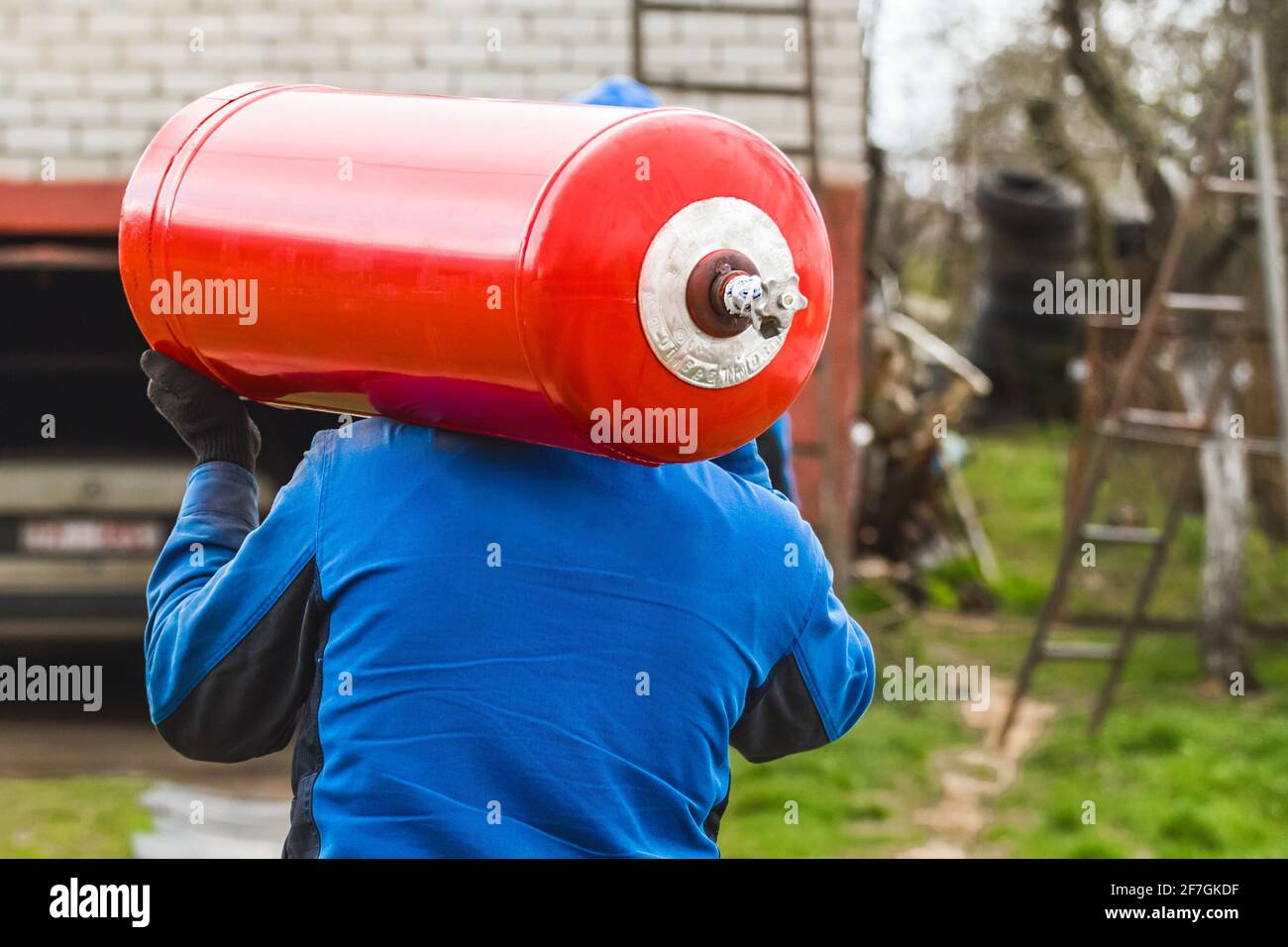 Ein männlicher Industriearbeiter geht mit einer Gasflasche zu einem ...
