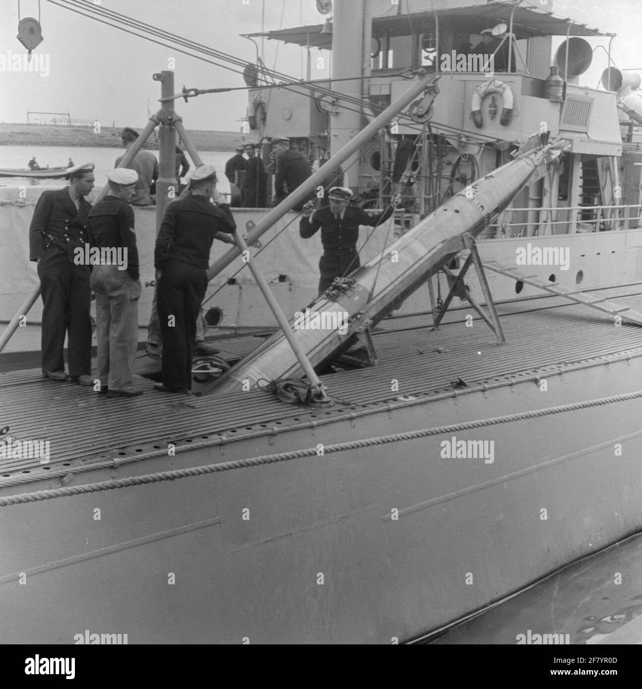 Beladen eines Torpedo in einem U-Boot. Neben dem U-Boot befindet sich ...