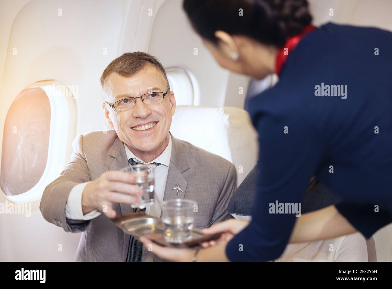 Passagiere haben Wasser von einer Flugbegleiterin im Flugzeug bedient ...
