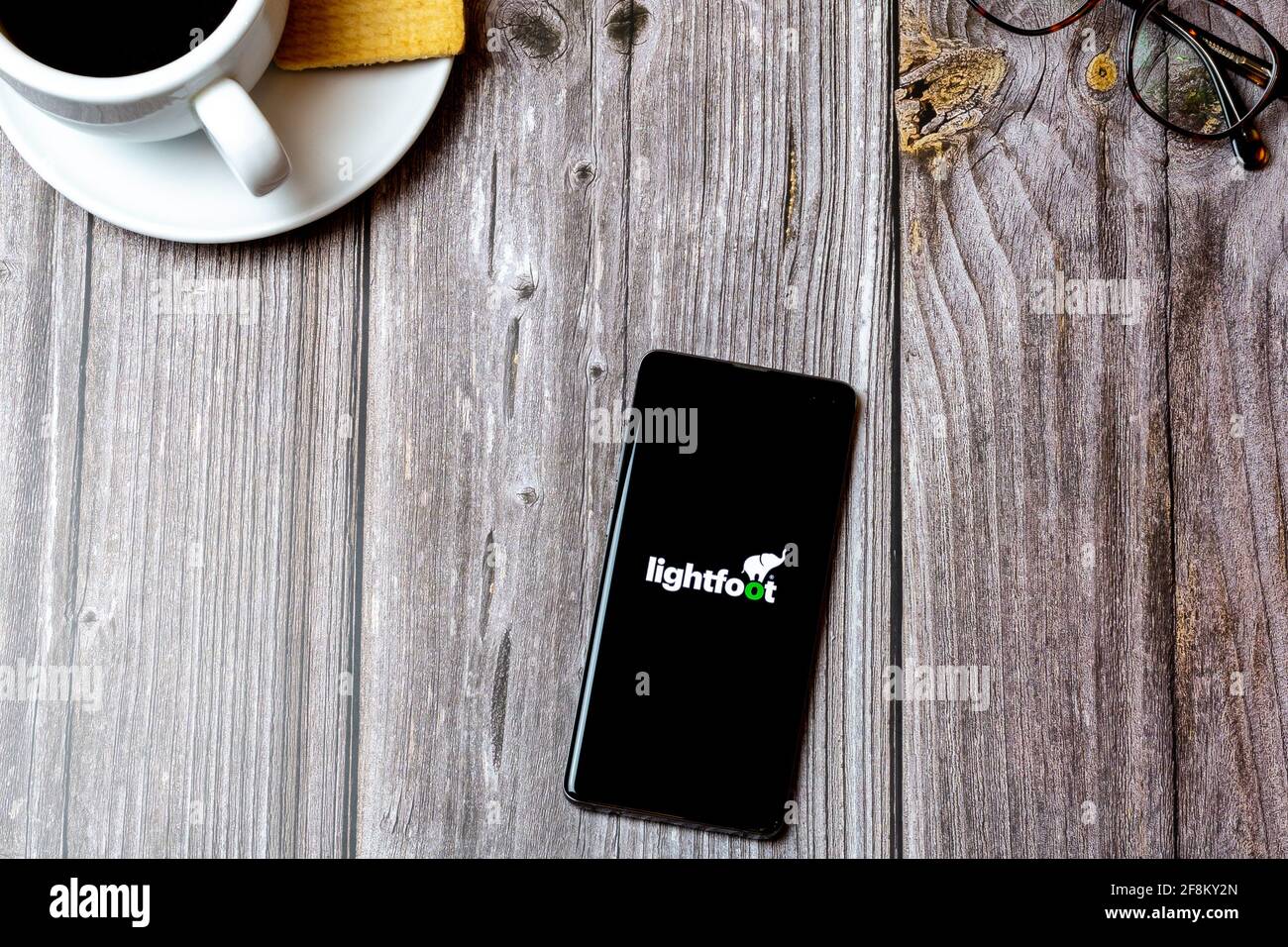 Ein Mobiltelefon oder Mobiltelefon, das auf einem Holzboden liegt Tabelle mit der Lightfoot-App ...