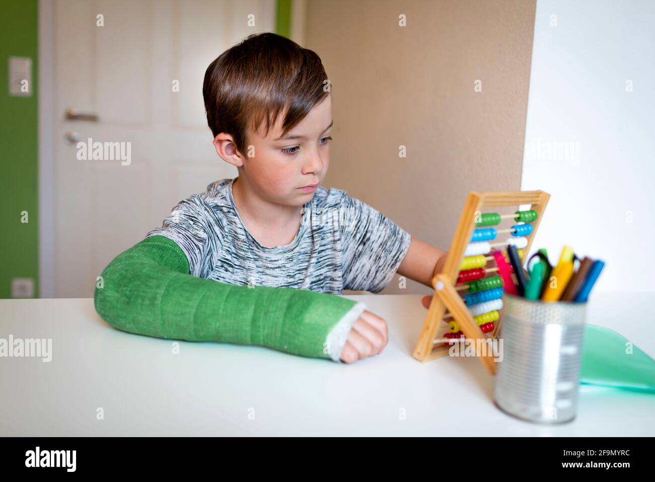 Ein cooler Junge mit grünem Armabdruck sitzt in seinem Zimmer Und lernt ...