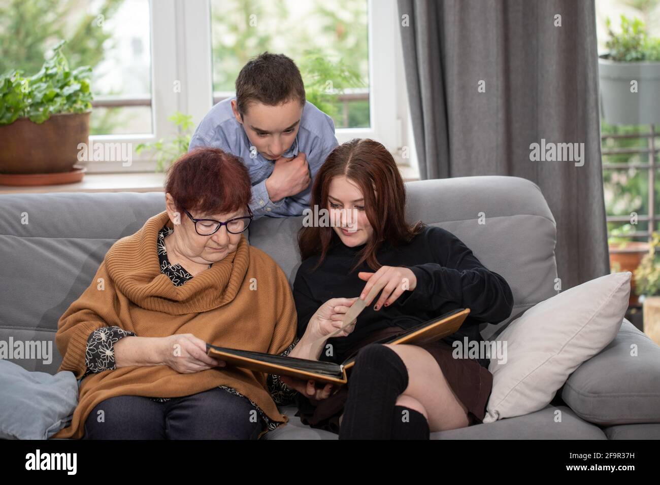 Familie mit mehreren Generationen, lächelnde Familie beim Betrachten des Fotoalbumes auf dem ...