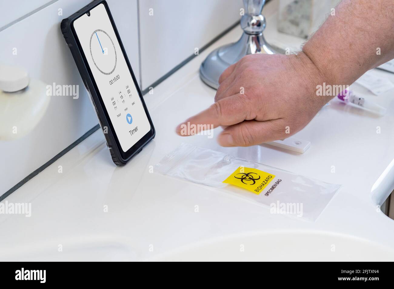 Ein Mann macht einen Corona-Selbsttest. Er stellt den Timer auf seinem ...