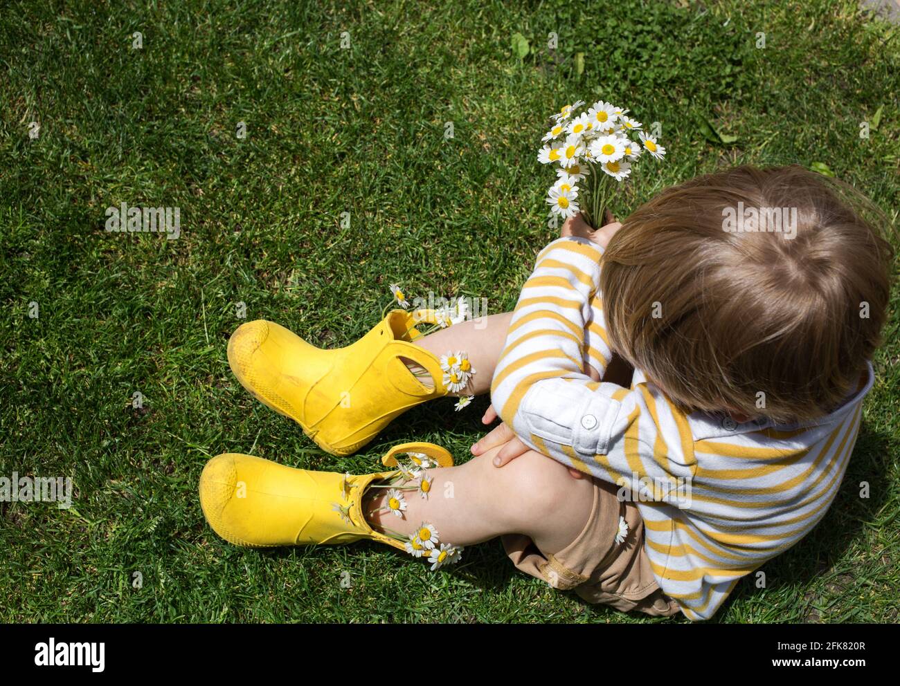 Ein unerkennbarer kleiner Junge in gelben Gummistiefeln mit einem ...