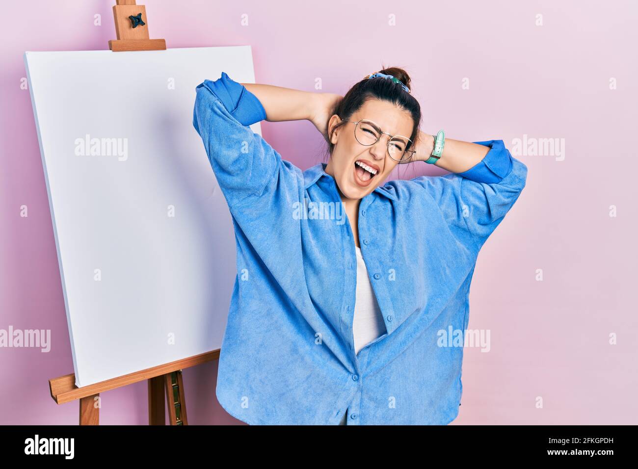 Junge hispanische Frau, die beim Maler Staffelstand steht, entspannt und streckt, Arme und Hände ...