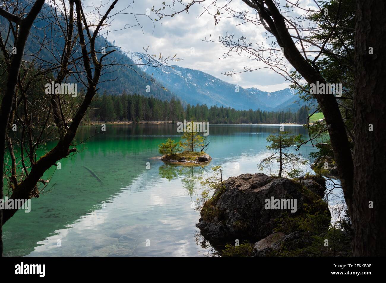 Felseninsel mit Kiefern, die auf ihr in Smaragd wachsen Grüner Alpensee ...