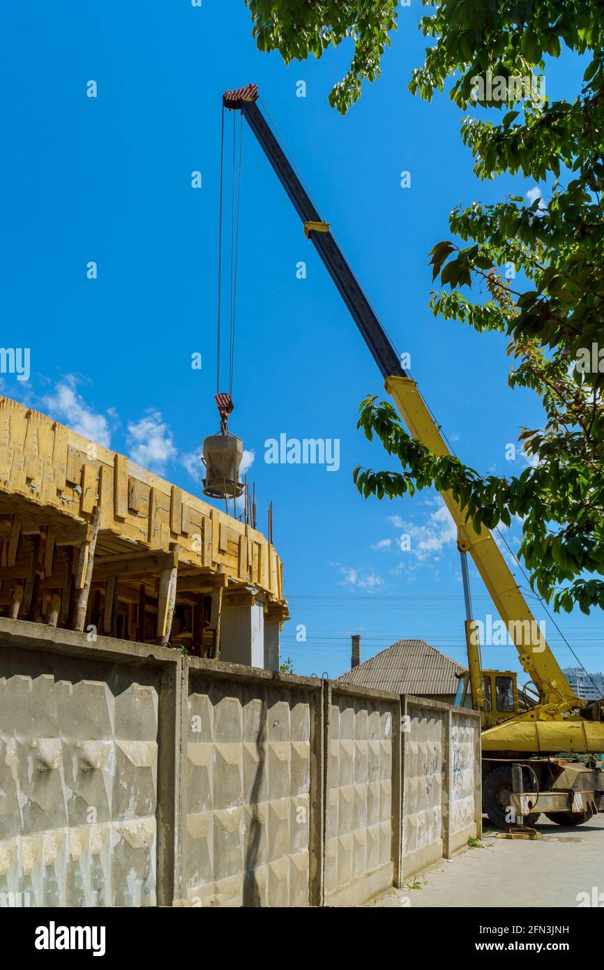 Riesiger Betonkübel, der mit dem Kran zur Schalung oben transportiert ...