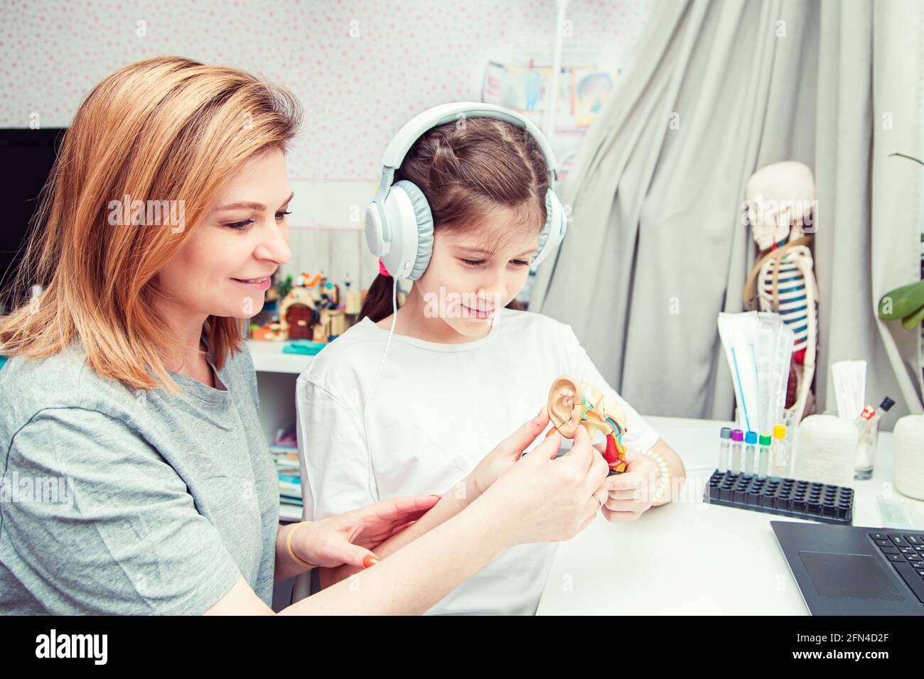Junges Teenager-Mädchen mit Mutter, die zu Hause menschliche Anatomie studiert. Ungewöhnliches ...