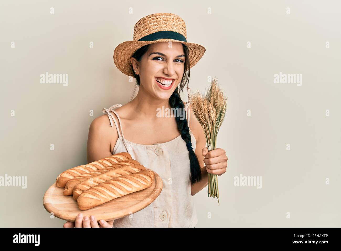 Junge hispanische Frau hält selbstgebackenes Brot und Spike Weizen ...