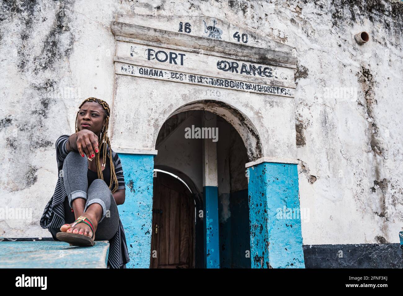 Afrikanische Frau auf einer Mauer eines historischen Ortes in Sekondi ...