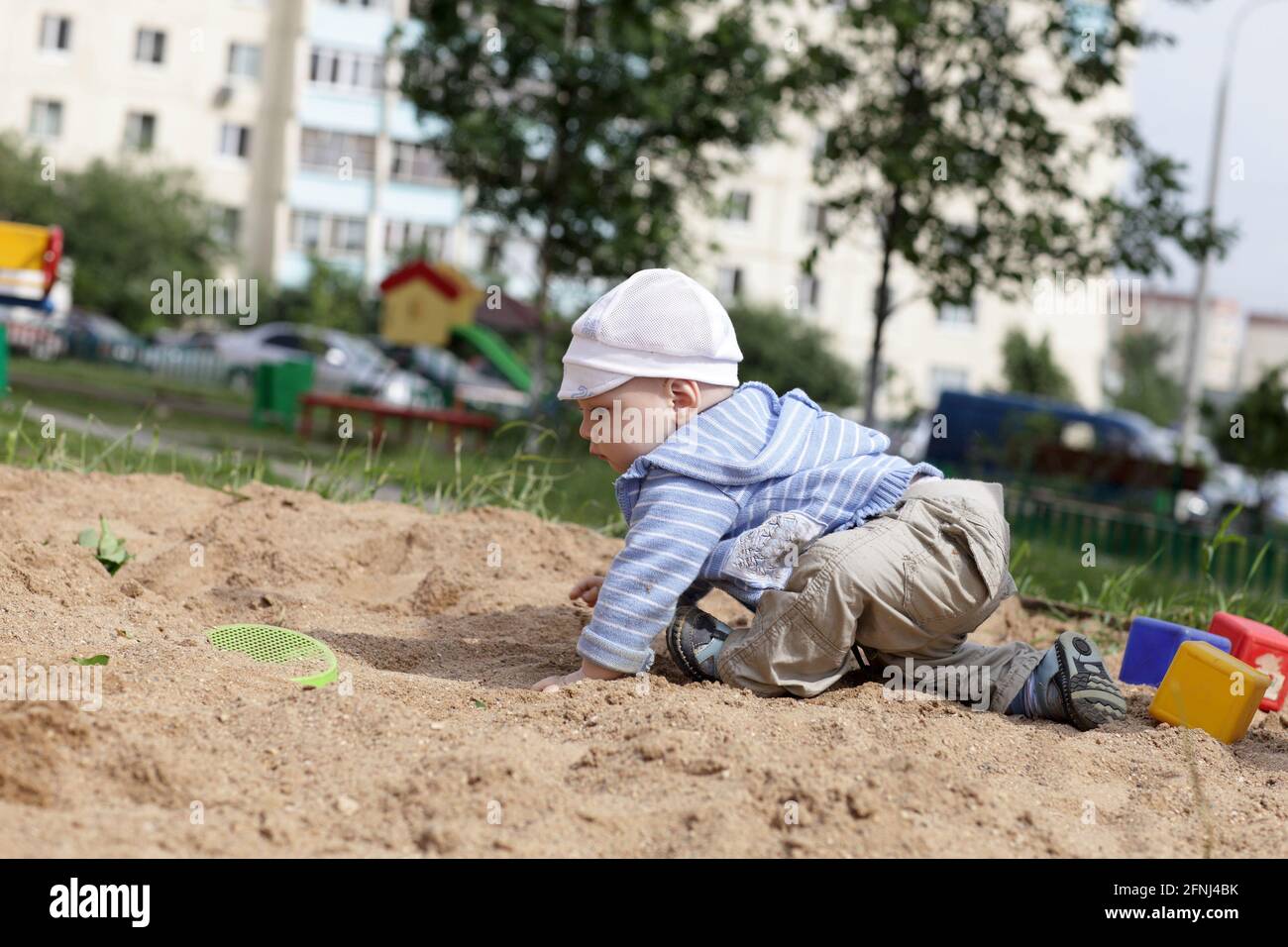 Das kleine Kind kriecht im Sandkasten auf dem Spielplatz ...
