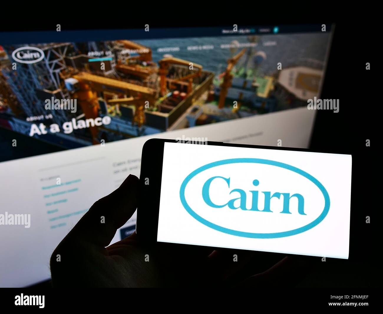 Person mit Mobiltelefon und Geschäftslogo des britischen Öl- und ...
