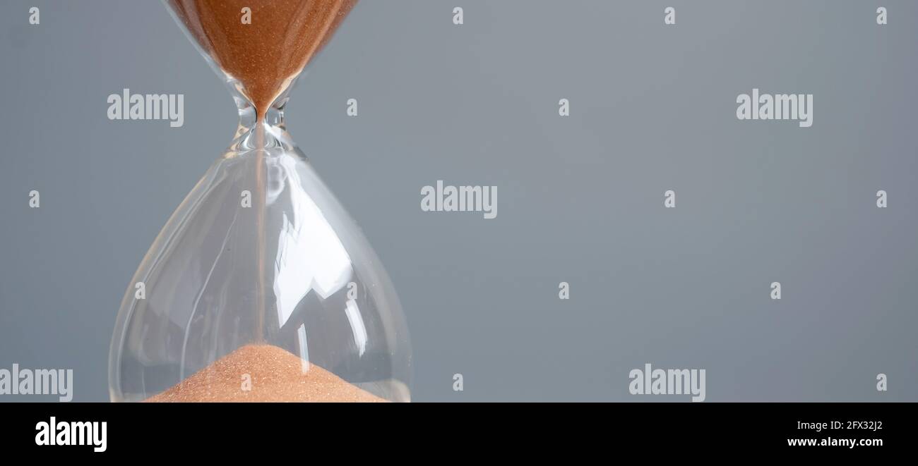 Sanduhr auf Tischbüro mit Kopierfläche, Sand fließt durch die Glühbirne ...