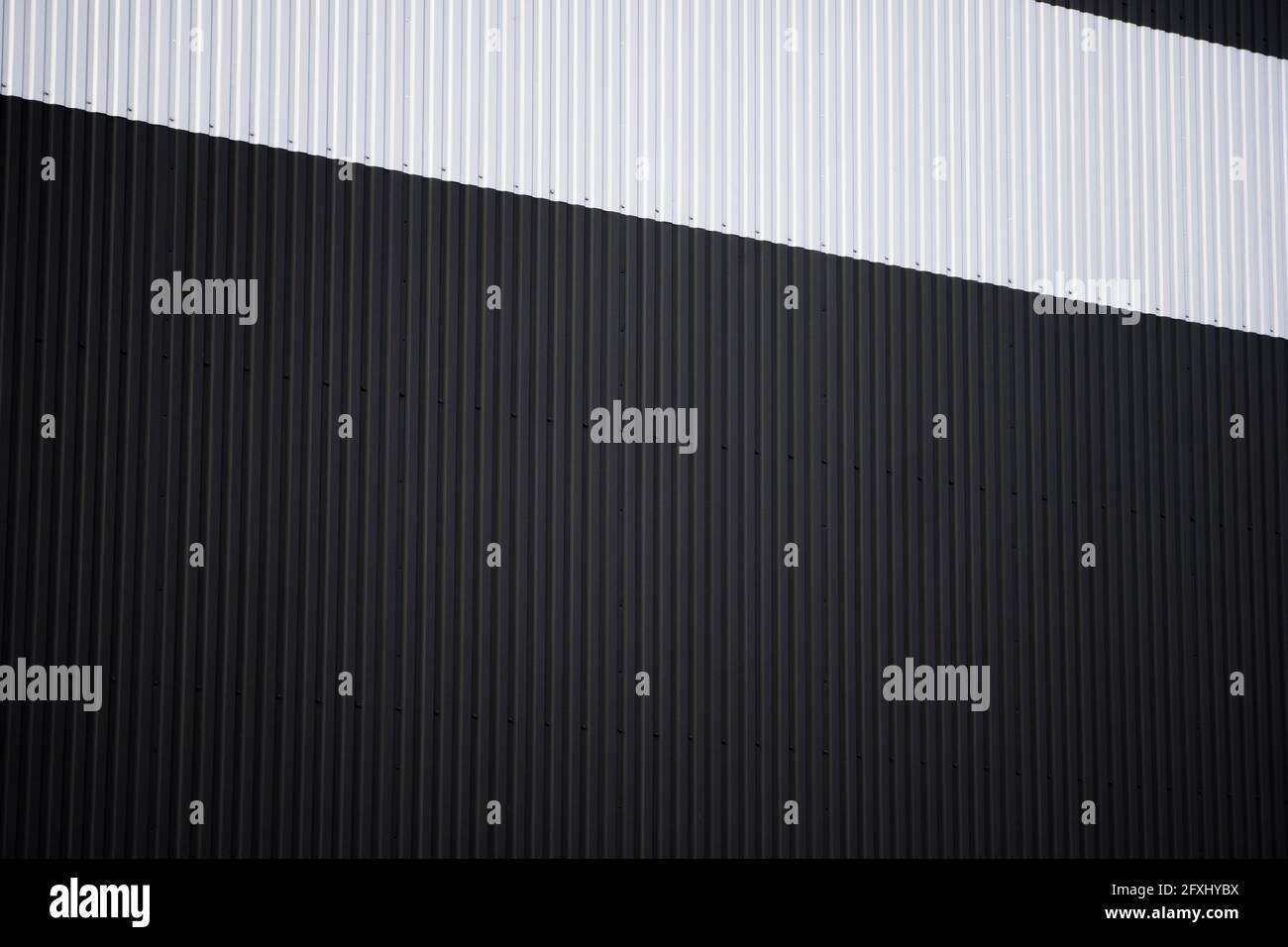 Schwarz-weißes Wellblech, das als Fassade eines Lagers oder einer ...