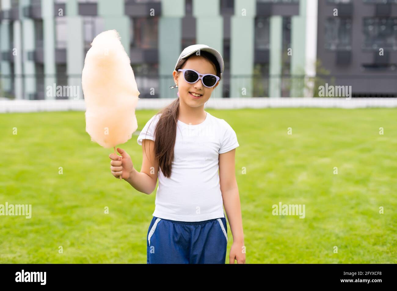 Liebenswert und ziemlich lockig kleines Mädchen essen süße Zuckerwatte ...