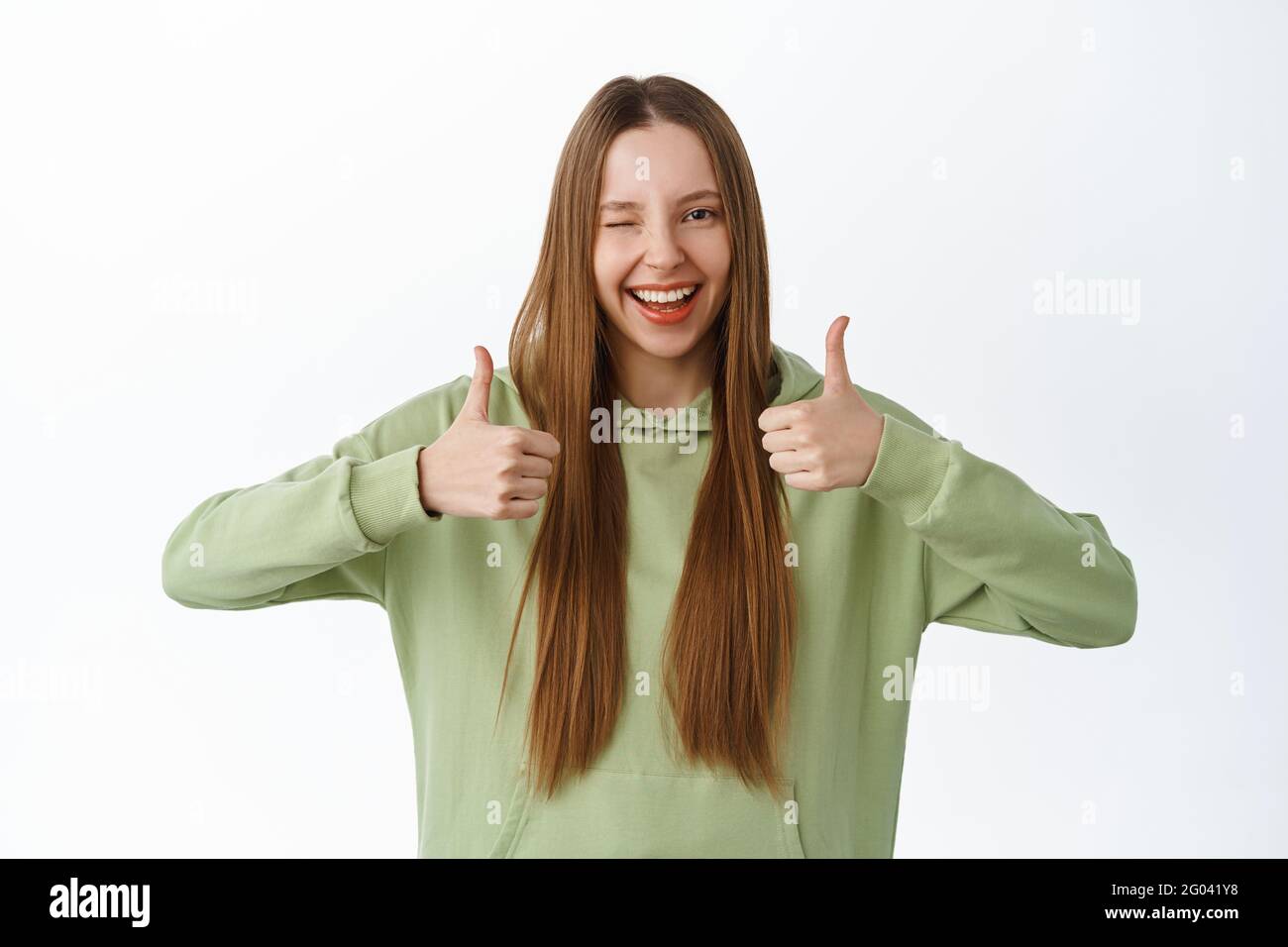 Positive Generation-z-Mädchen winkend und lächelnd, zeigt Daumen nach ...