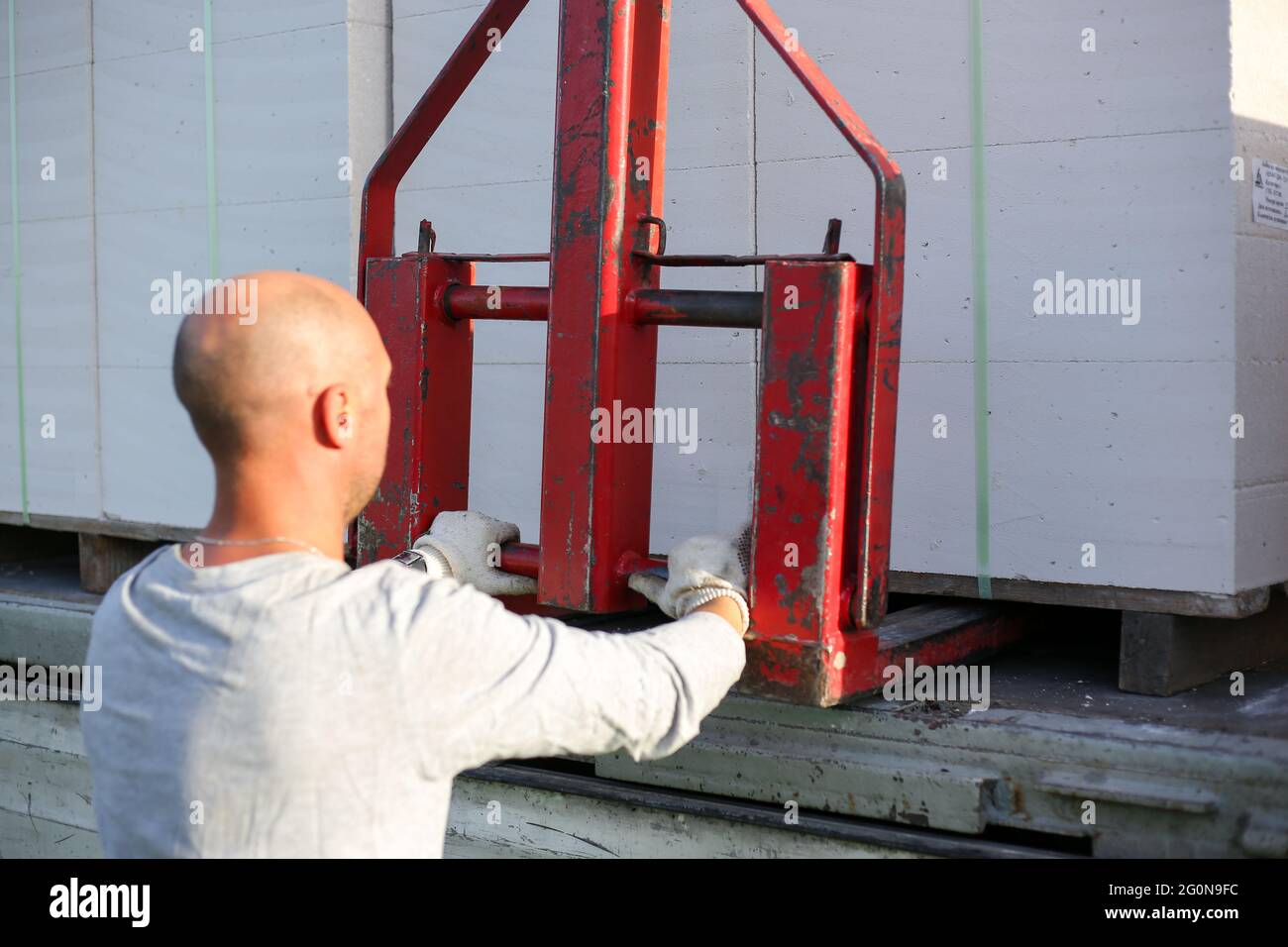 Entladen von Bausteinen von einem LKW mit einem Kran. Hydraulischer ...