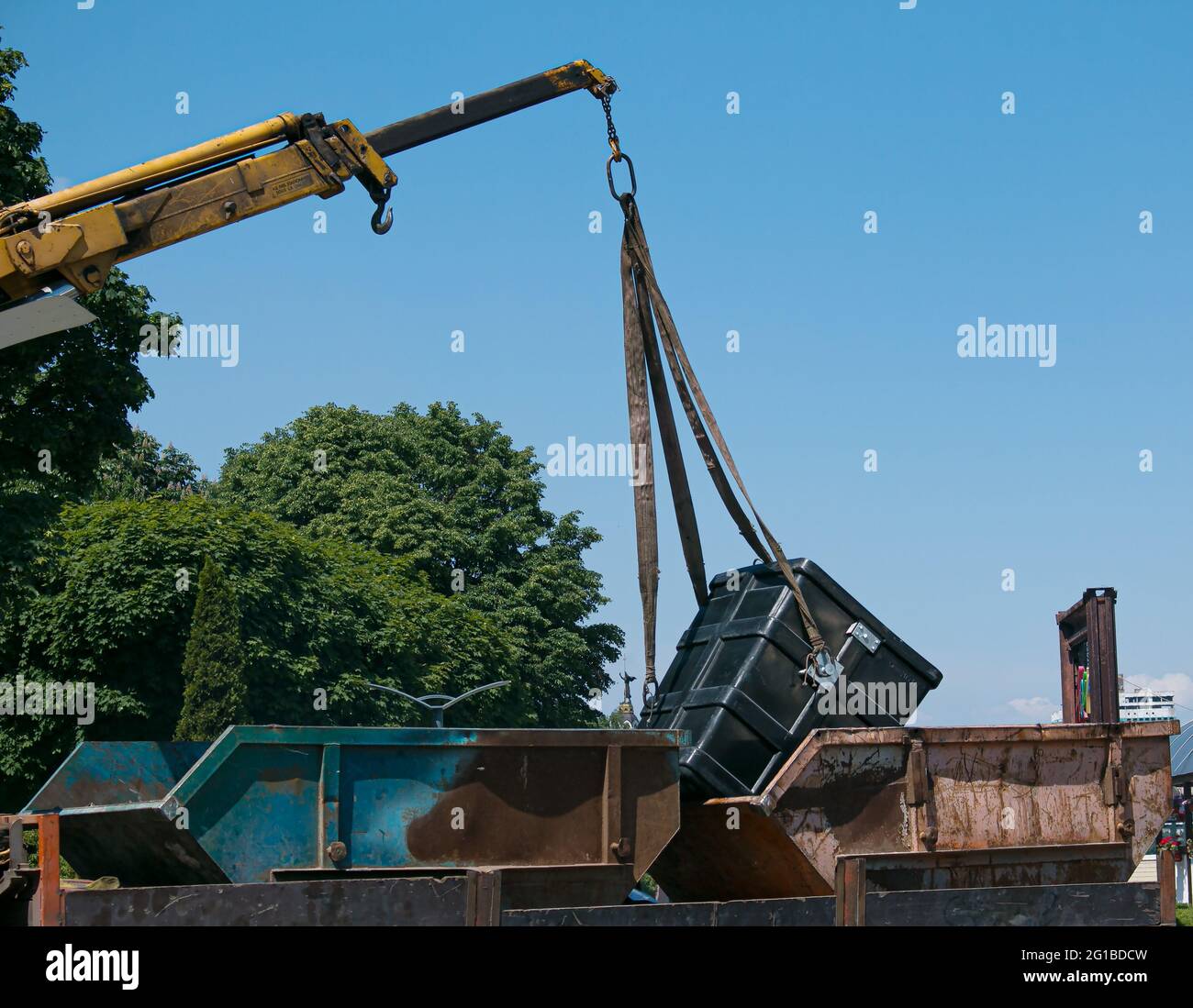 Verladen von Müllcontainern mit einem Kran in einen LKW. Slinger ...