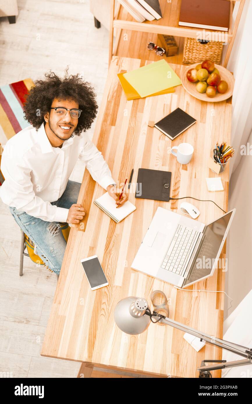 Kreativer Mann macht Notizen in einem Notizbuch, das arbeitet oder ...