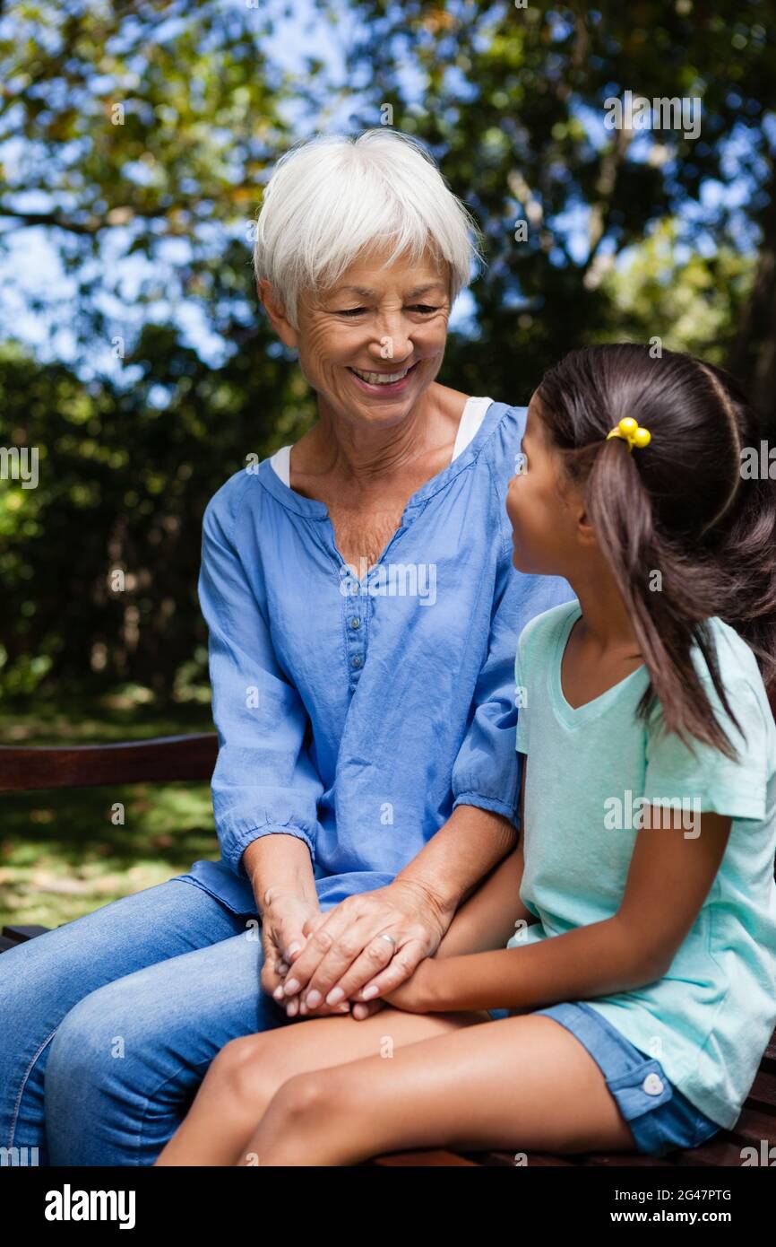 Lächelnde Enkelin und Großmutter halten sich die Hände, während sie auf ...