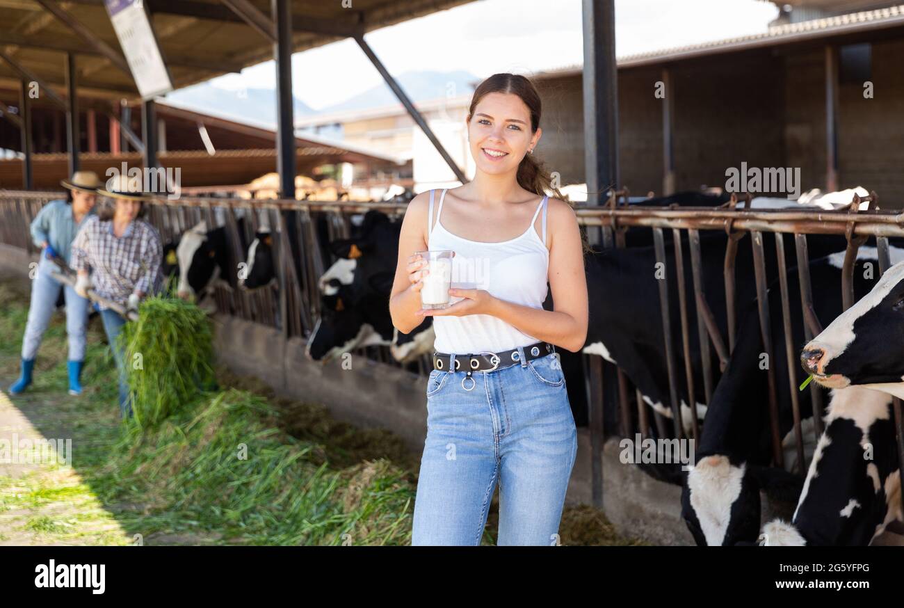 Melkerin posiert mit einem Glas Milch auf einem Milchviehbetrieb ...