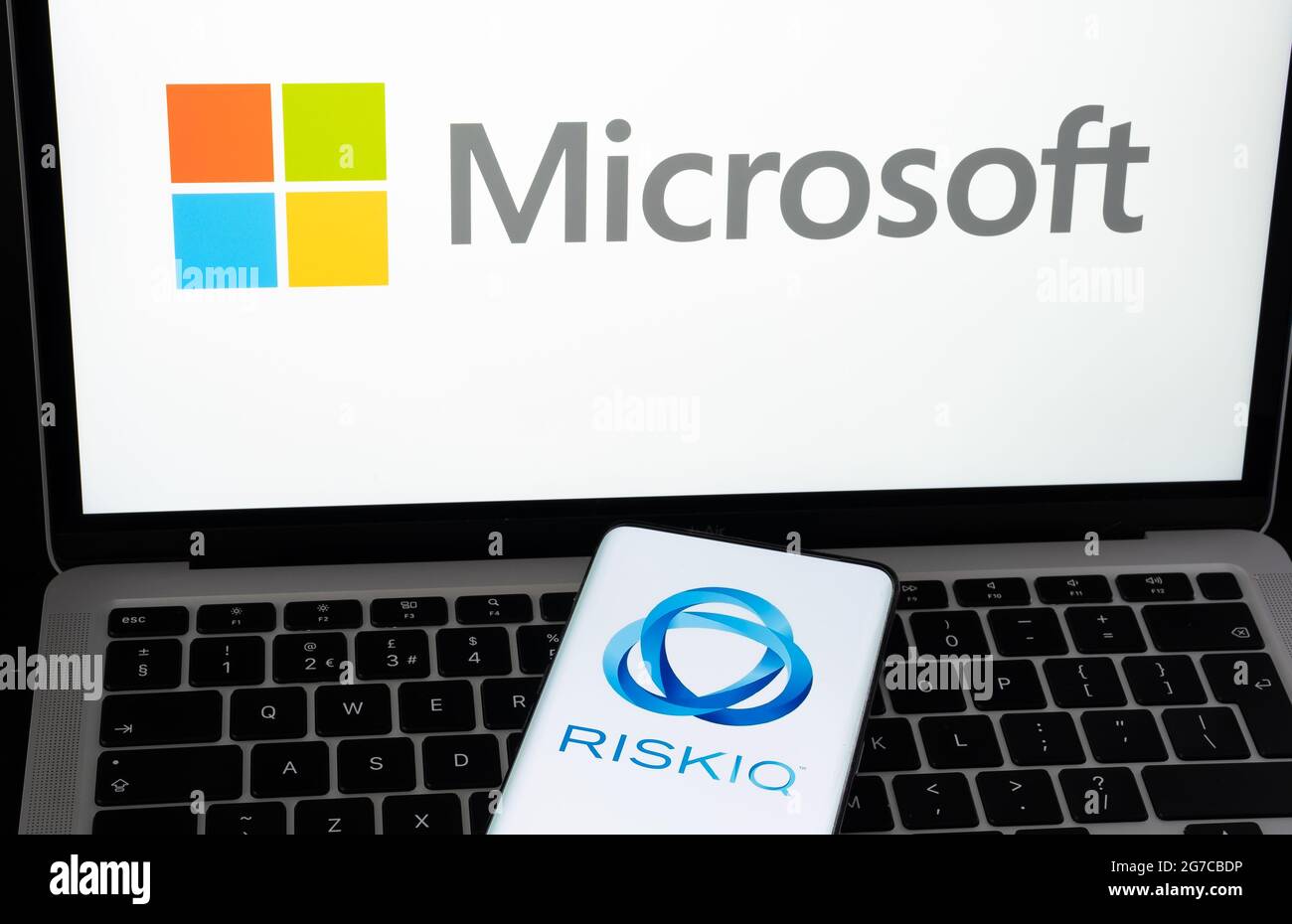 Das Unternehmenslogo von RiskIQ auf dem Smartphone und das Microsoft-Logo auf dem verschwommenen ...